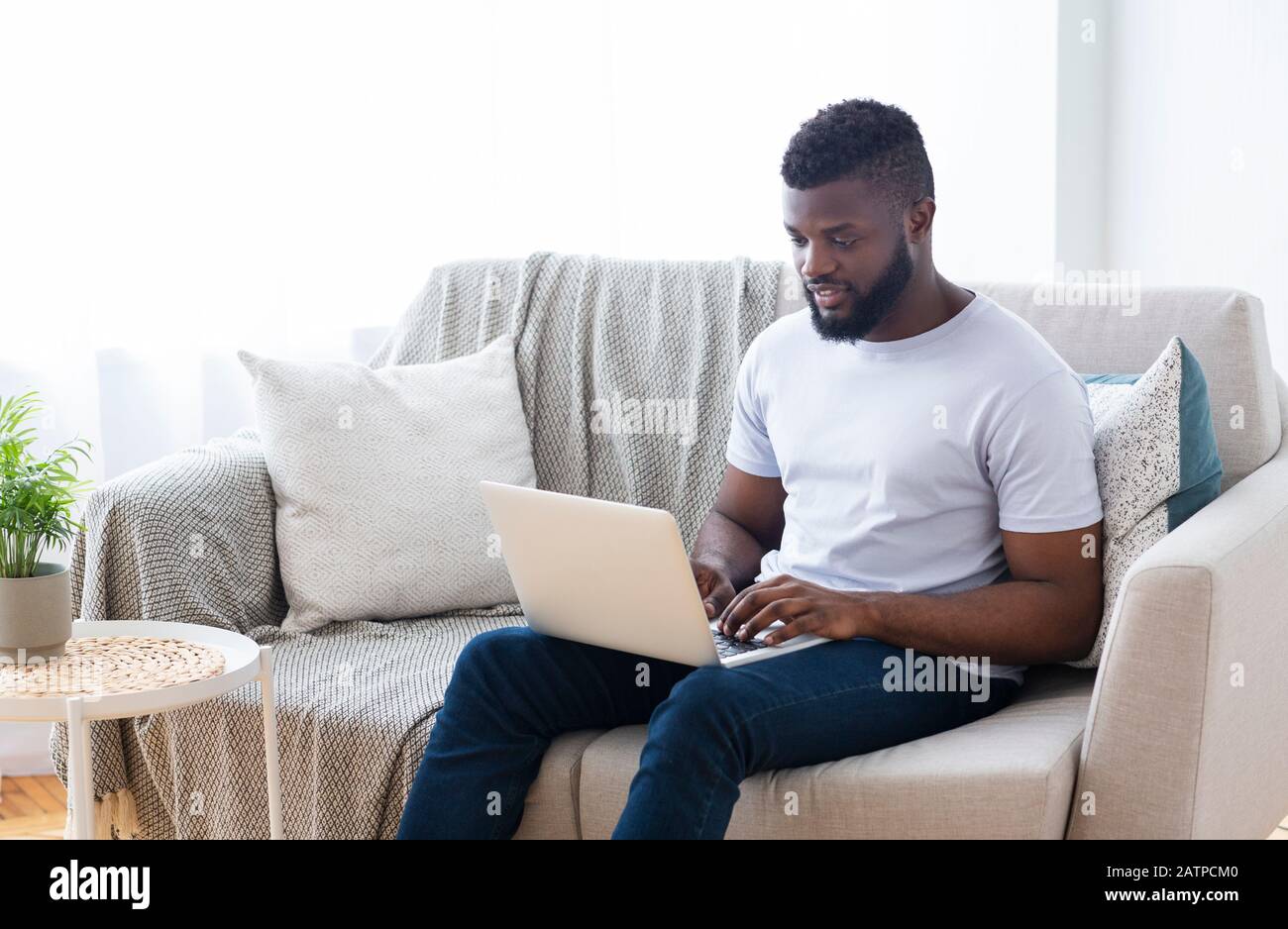 Young african man working on laptop online at home Stock Photo - Alamy