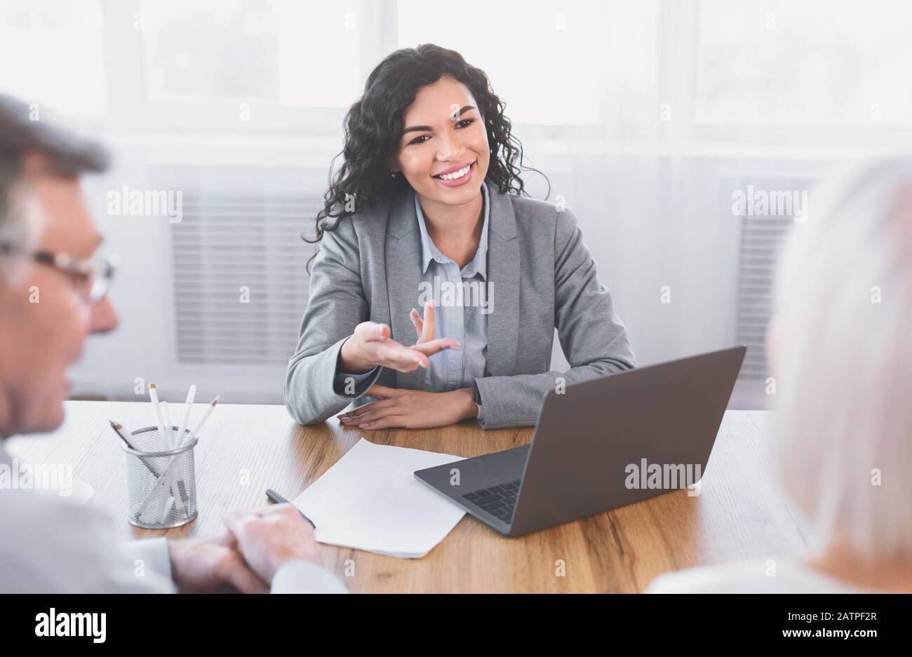 Beautiful latina travel agent is working with clients Stock Photo - Alamy