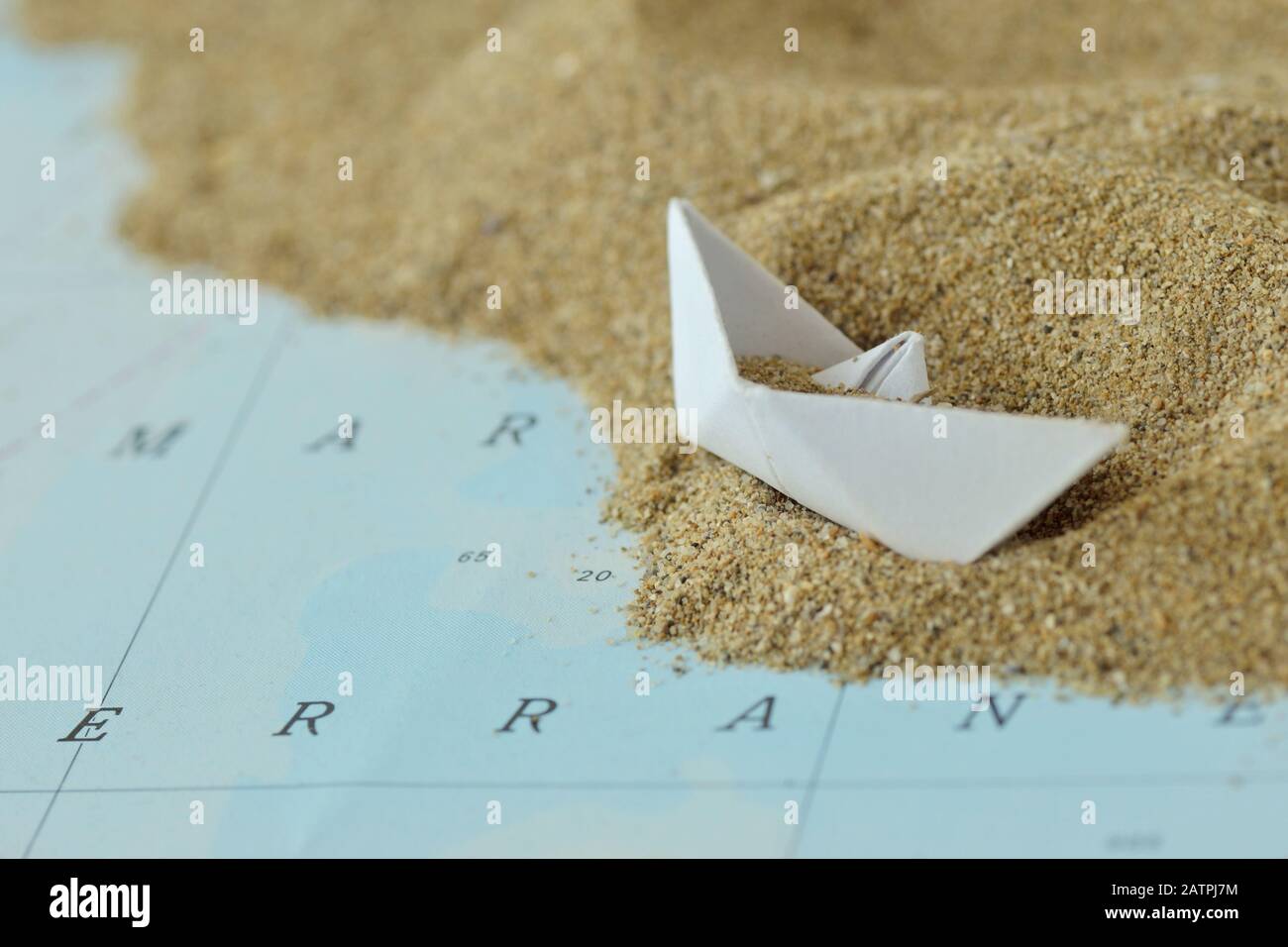 Overturned paper boat on a map with sand - Immigration concept Stock ...