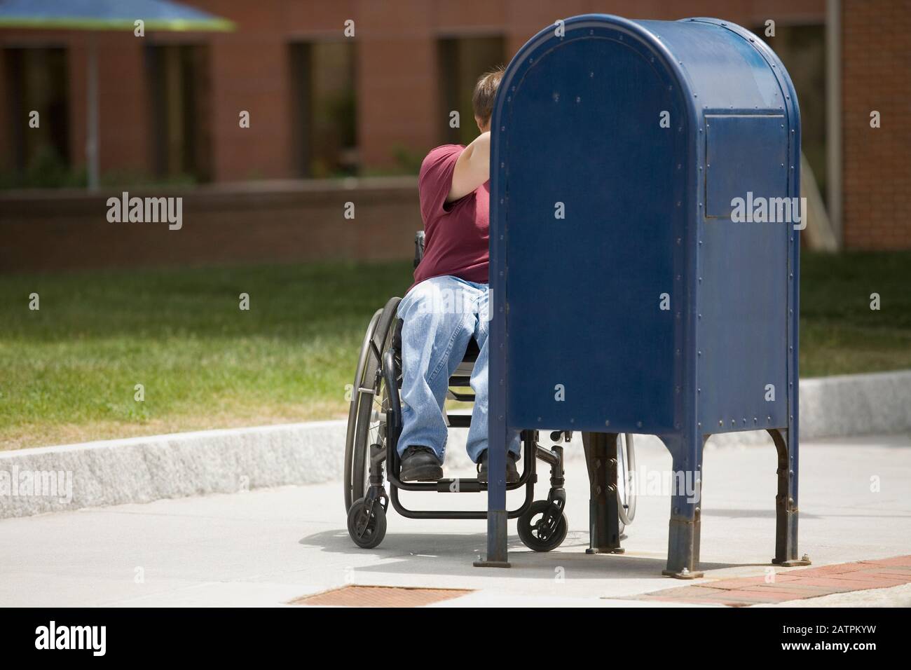 Woman sitting in a wheelchair and putting mail into a mailbox Stock ...