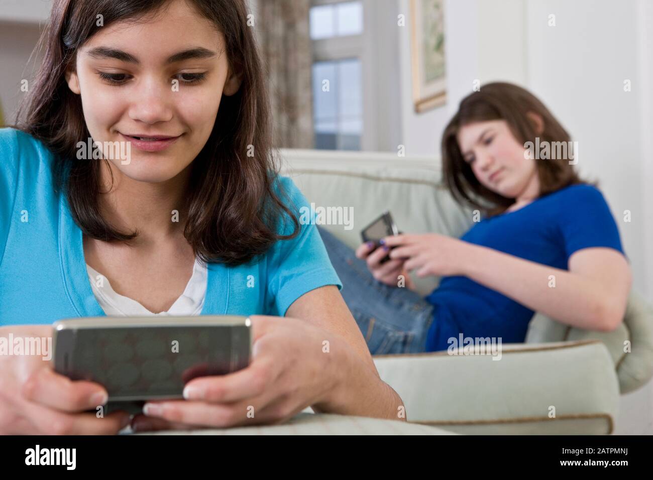 Two teenage girls using smart phones Stock Photo - Alamy