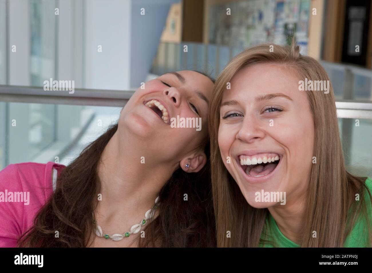 Two teenage girls laughing together, one looking at the camera Stock ...