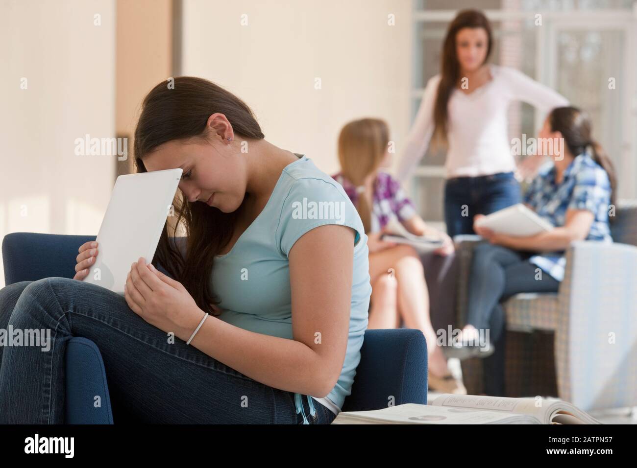 Teenage girl using laptop at school and hiding the screen from others ...