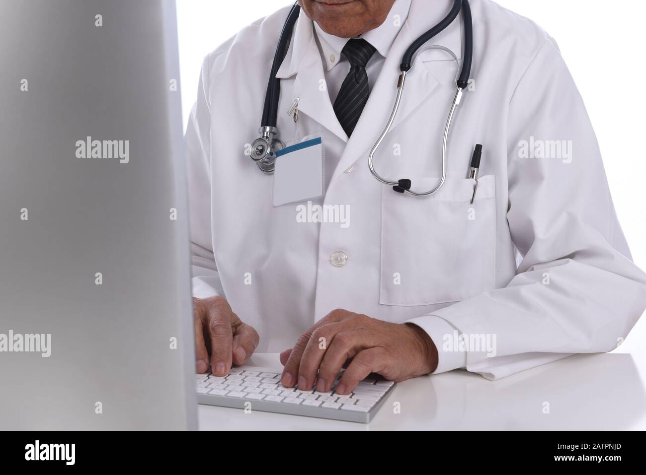 Closeup of a docor partially behind his computer screen as he types on ...