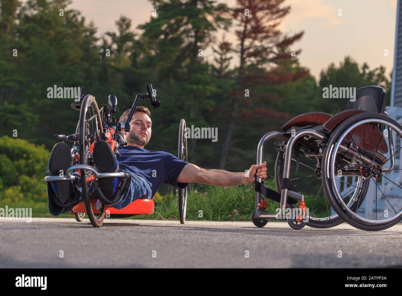 A man with a disability lays on an adaptive bicycle while holding onto ...