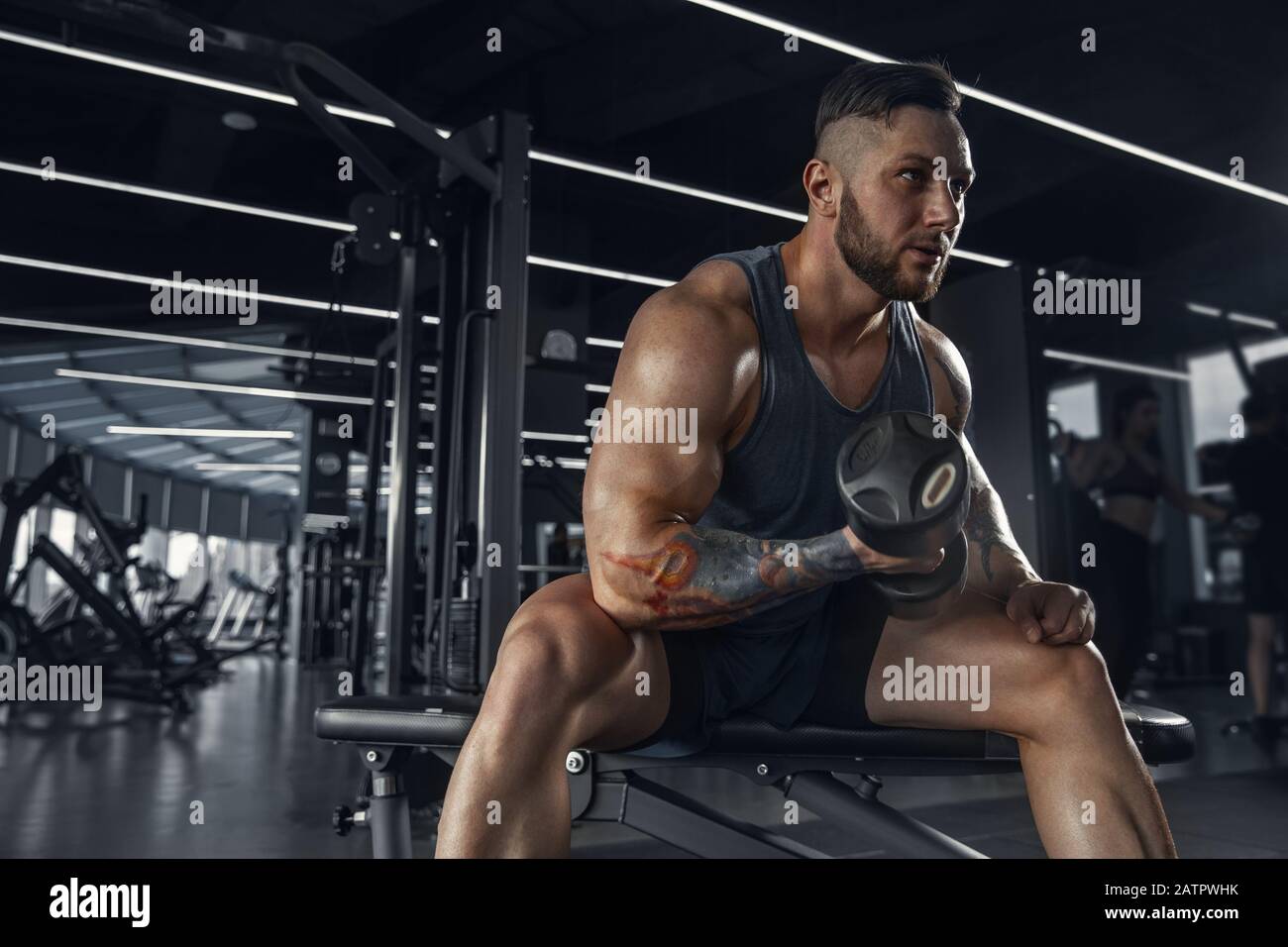 Confident. Young muscular caucasian athlete practicing in gym with the ...