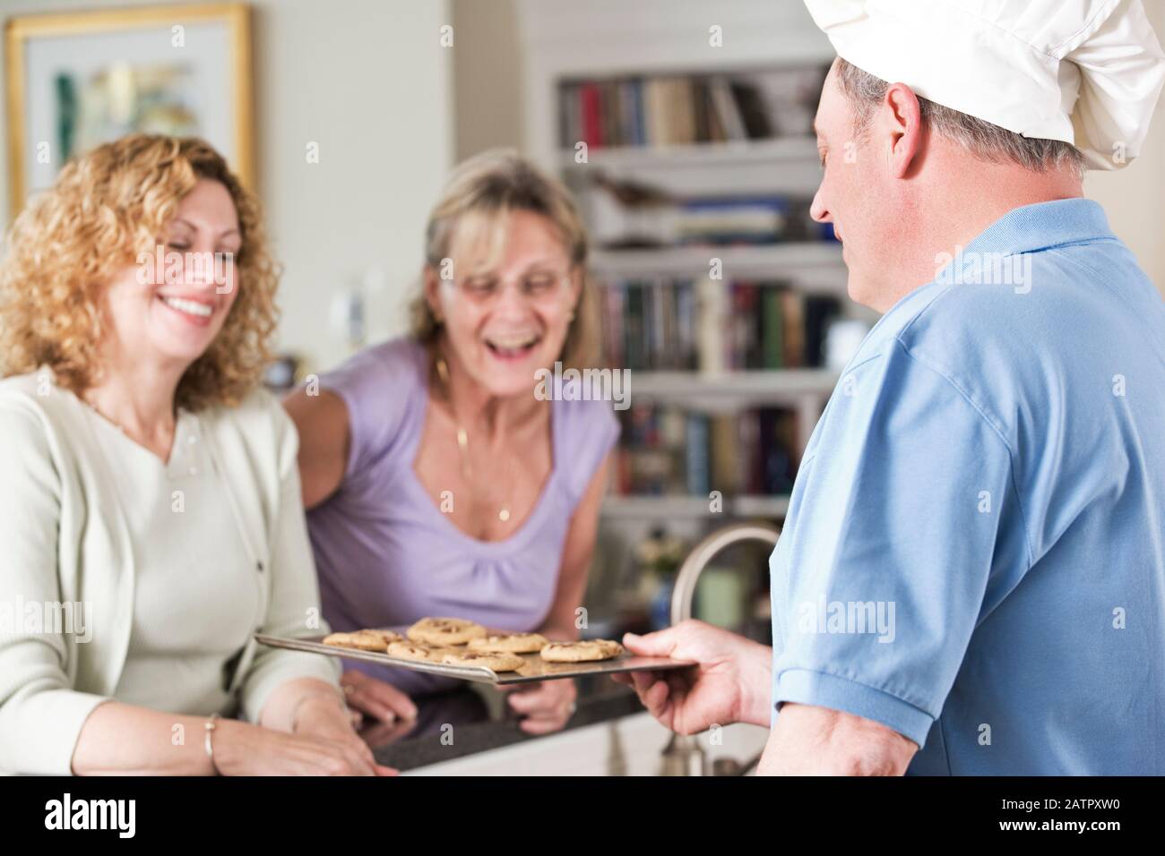 Chef serving cookies to mature women at home Stock Photo - Alamy