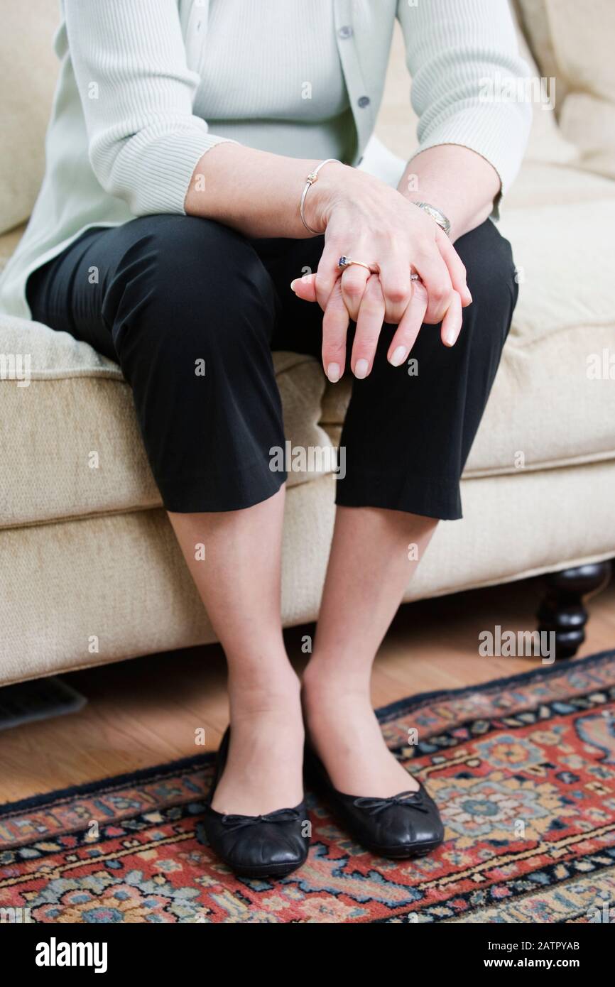 Low section of a woman sitting on a couch Stock Photo - Alamy