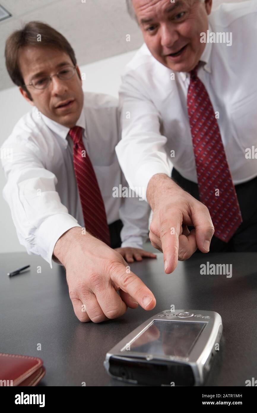 View of man pointing at a mobile phone in an office Stock Photo - Alamy