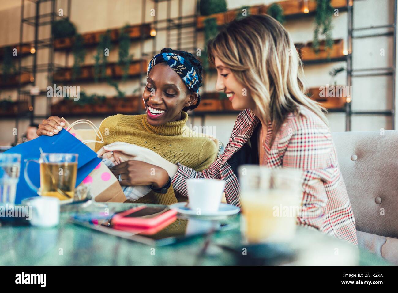Two female friends talking at a coffee shop, after shopping Stock Photo ...