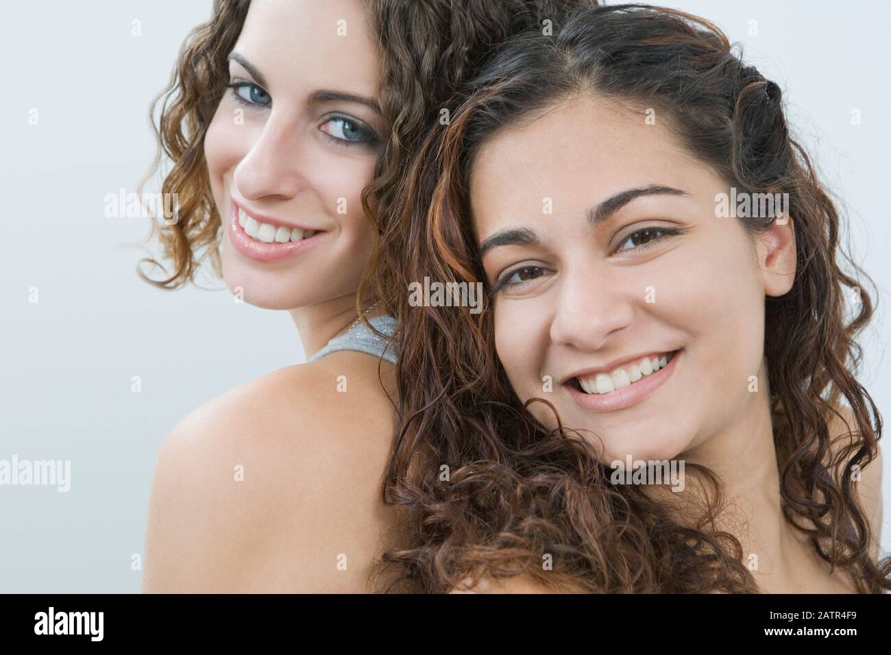 Portrait of two teenage girls smiling back to back Stock Photo - Alamy