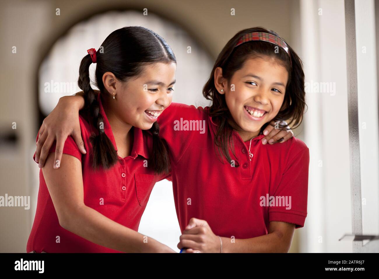 Two smiling schoolgirls standing with their arms around each other ...