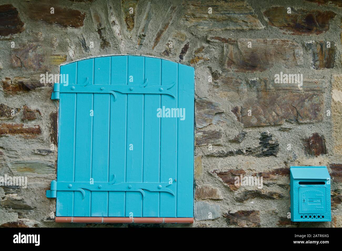 Turquoise folding shutter and letter box in a natural stone wall Stock ...