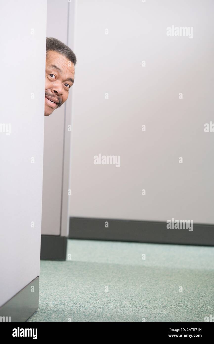 Portrait of a businessman peeking through a cubicle Stock Photo - Alamy
