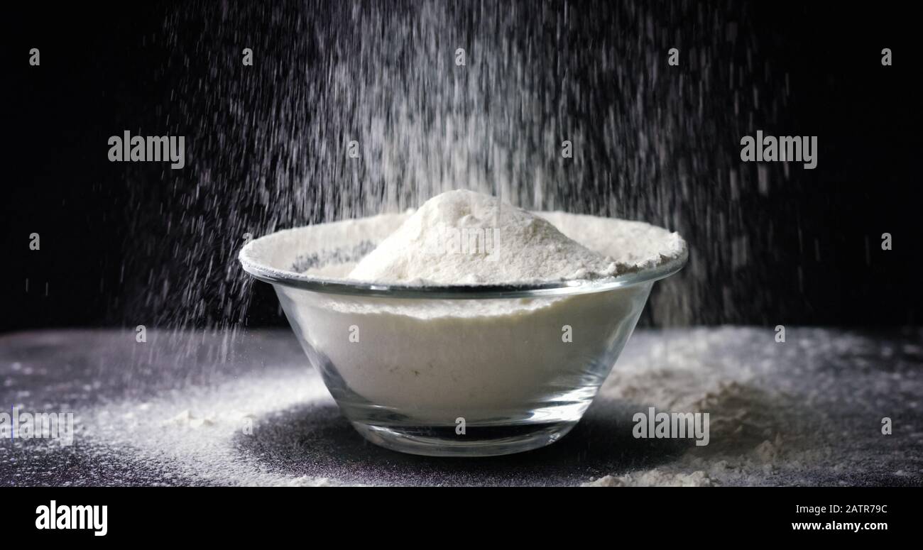 Flour is falling into a bowl in slow motion on black background Stock ...