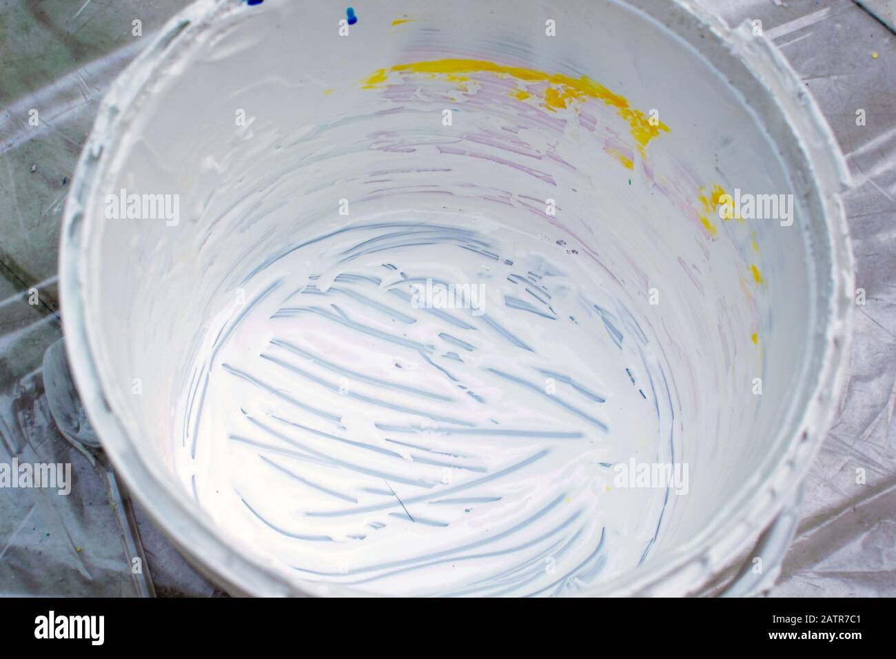 Empty bucket from under the white paint on the cellophane-covered floor ...