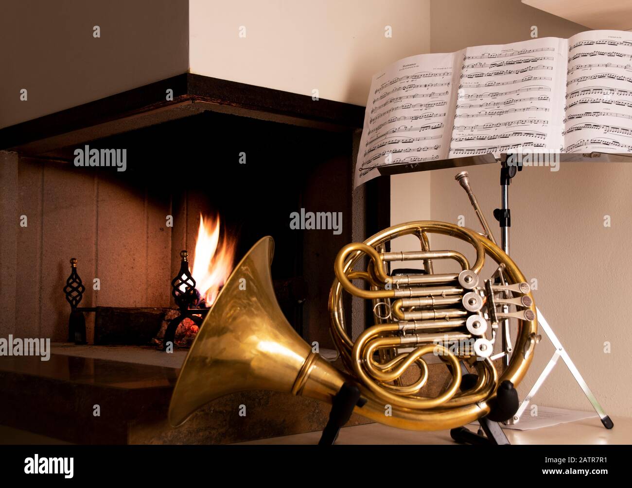 Open music score on a stand with brass horn in front of a burning fire ...