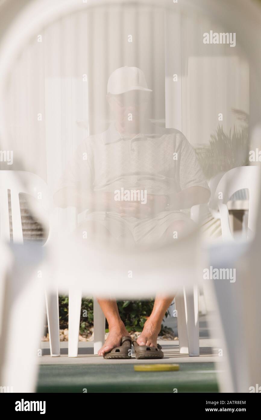 Senior man viewed through the back rest of a chair Stock Photo - Alamy