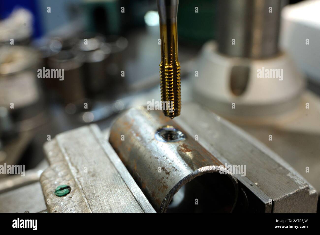 Nut tap making thread on the tube section, tapping machine Stock Photo ...
