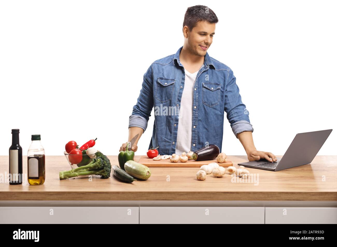 Young man cooking on a counter and looking at a laptop isolated on ...