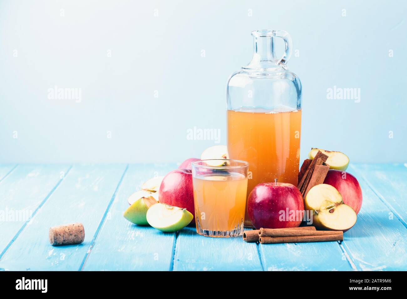 Fresh organic apple cider or apple juice with with cinnamon on the blue ...