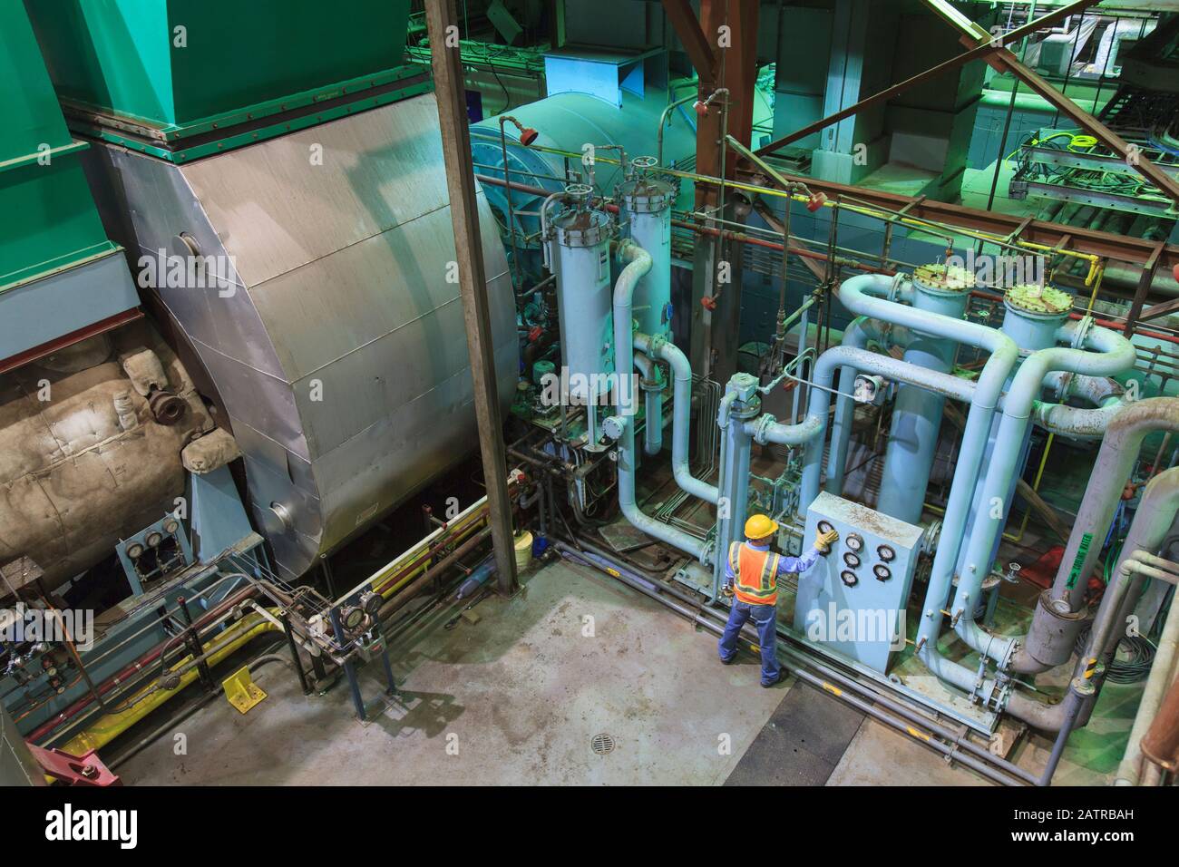 Worker wearing hard hat and reflective vest using equipment with gauges ...