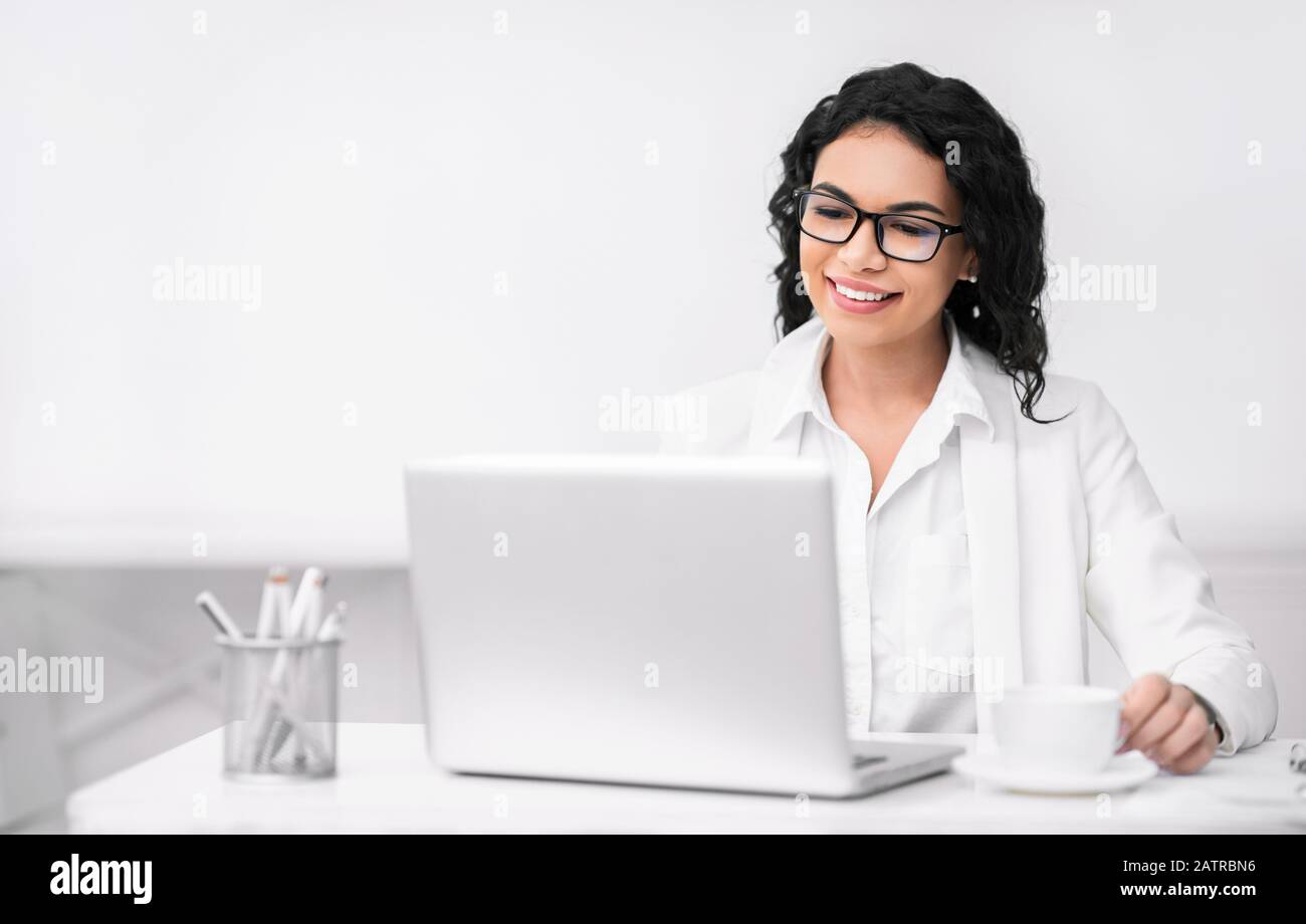 Smiling girl drinking tea and using personal computer Stock Photo - Alamy