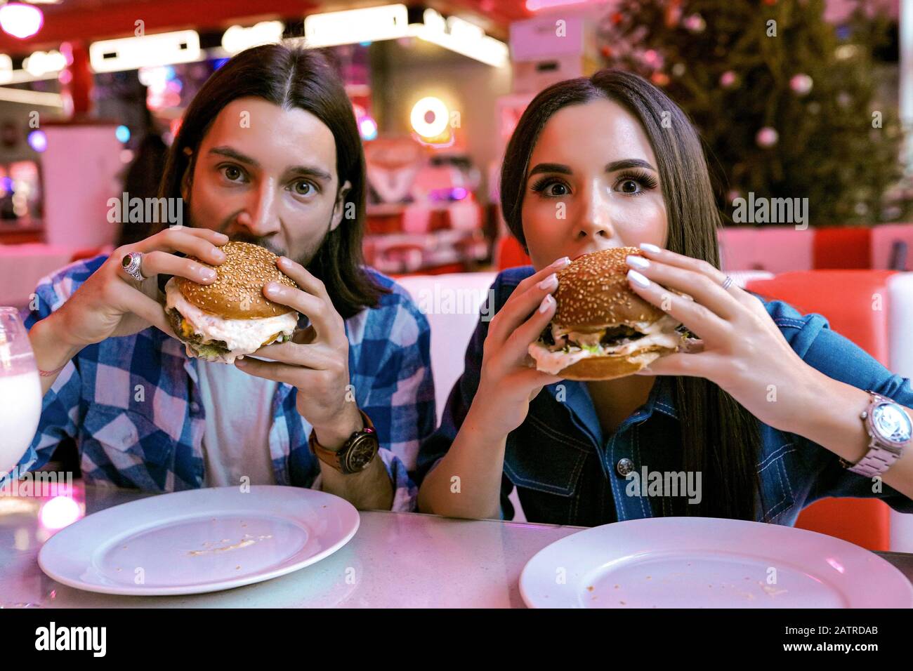 Modern lovely couple enjoys their amazing tasty meal, burger with meat ...