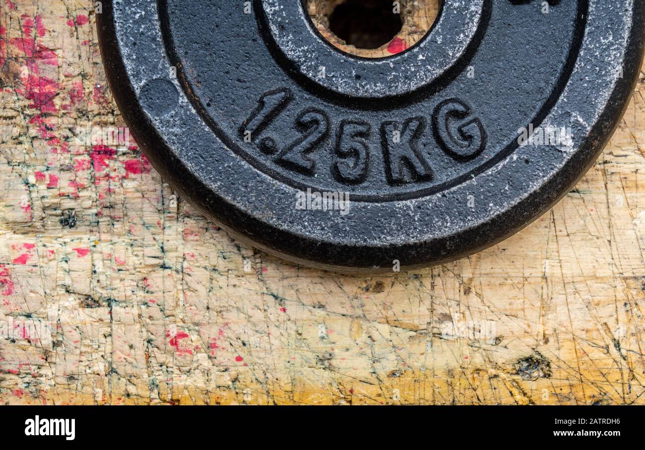 Black iron metal gymnastic disk weight on wooden workbench stained ...