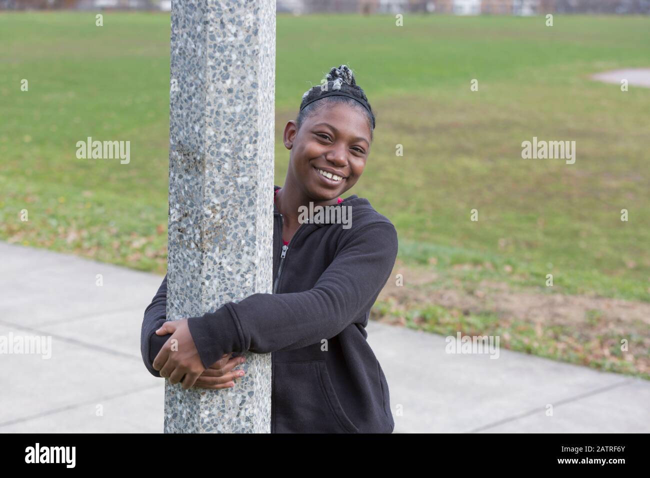 Portrait of a happy Teen suffering from Bipolar Disorder hugging a pole ...