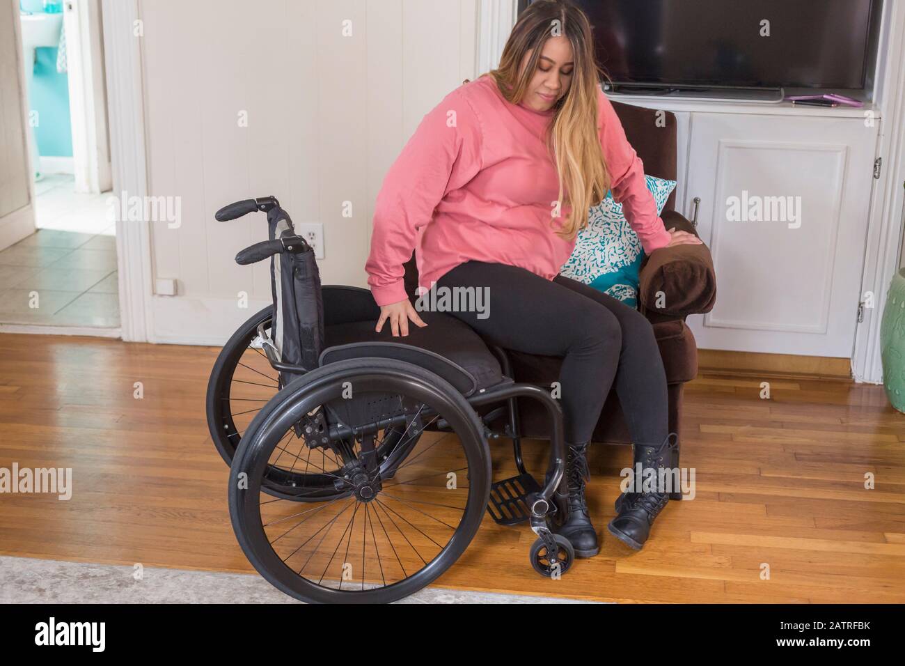 Woman with Spinal Cord Injury getting into her chair Stock Photo - Alamy