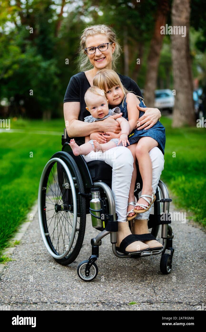 A paraplegic mom carrying her daughters on her lap while using a ...