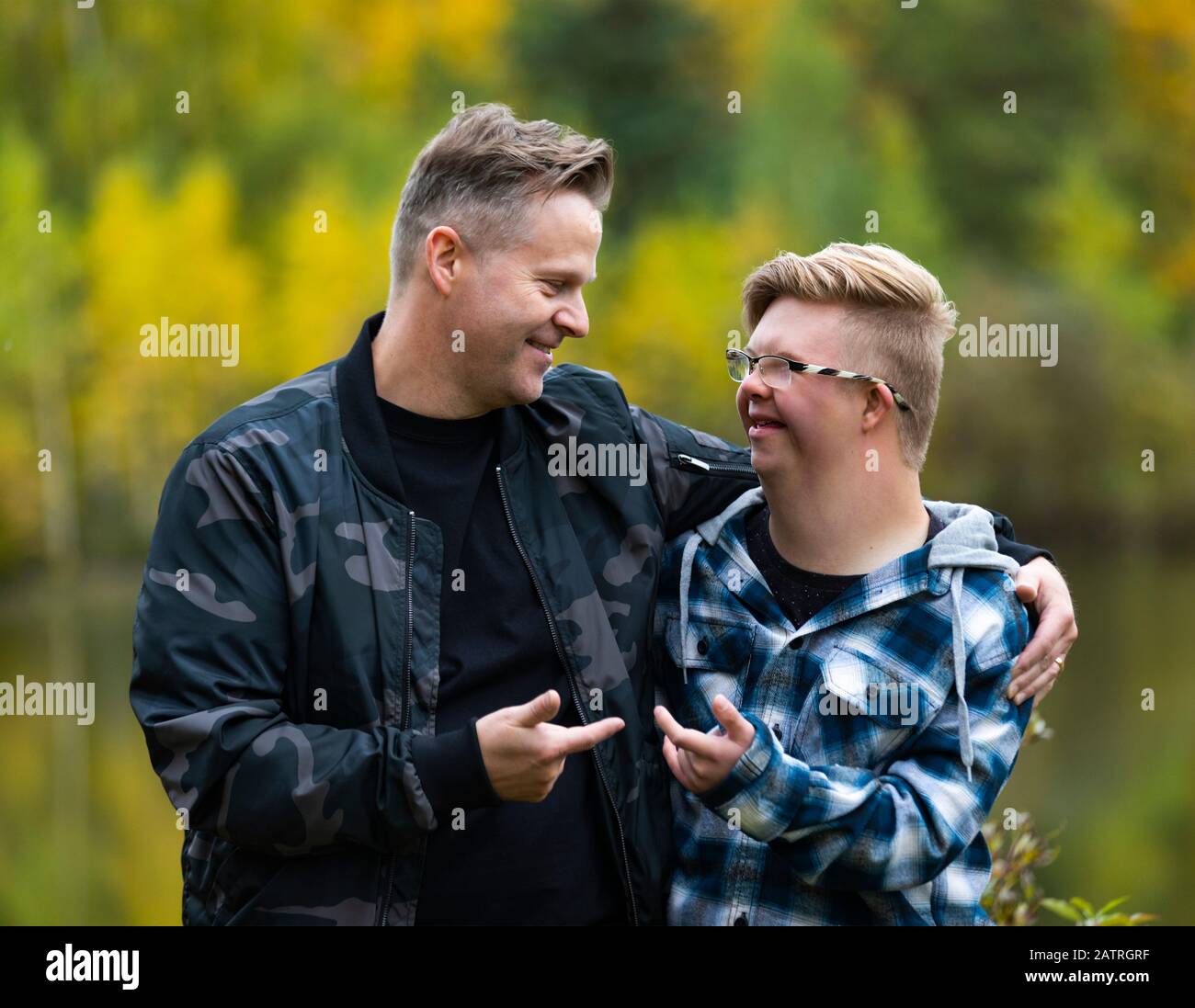 A young man with Down Syndrome and his father enjoying each other's ...
