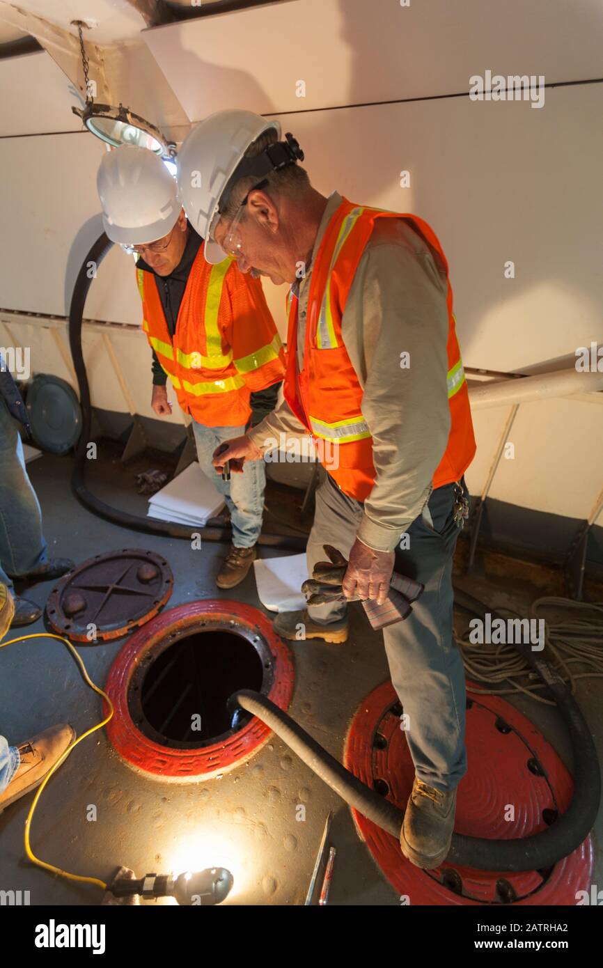 Environmental cleanup engineers in hold of ship cleaning hazardous ...