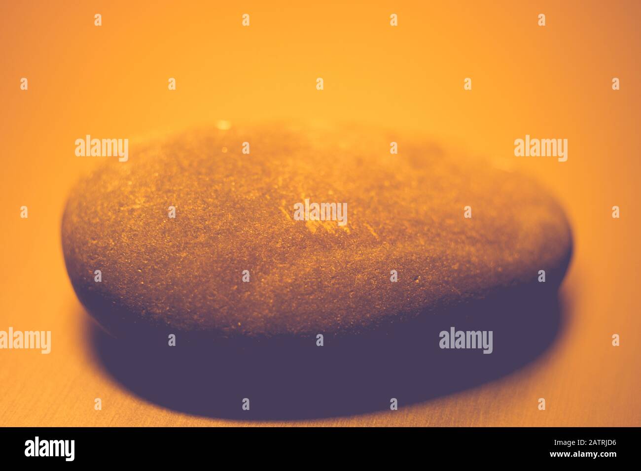 One big pebble stone on the table, orange light Stock Photo - Alamy