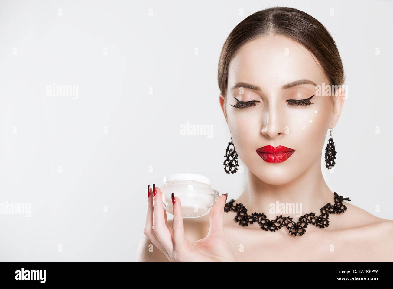 Drops of cream on face. Beautiful model showing applying cosmetic cream ...