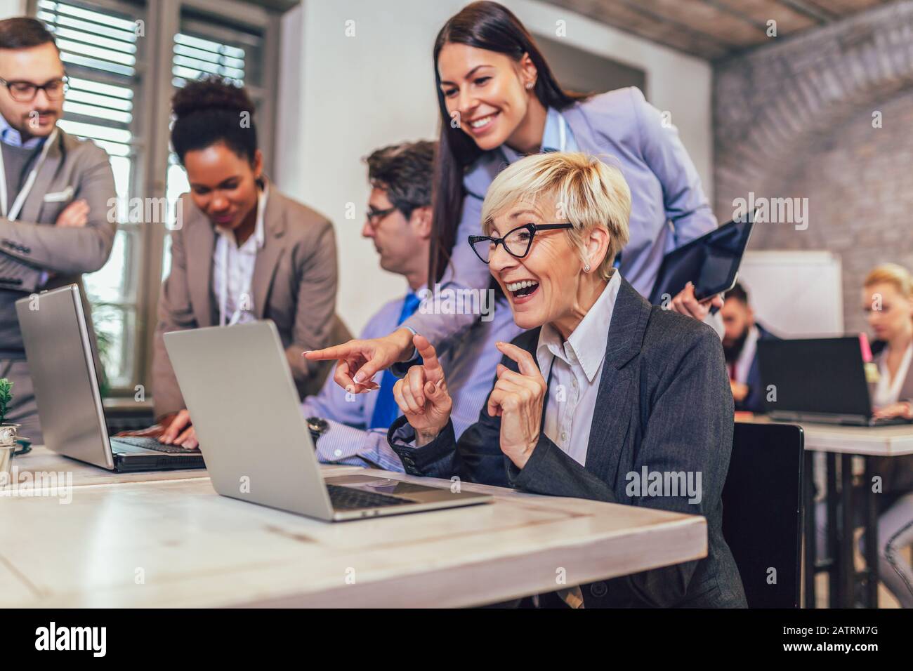 Smiling young manager helping senior worker with computer work in ...