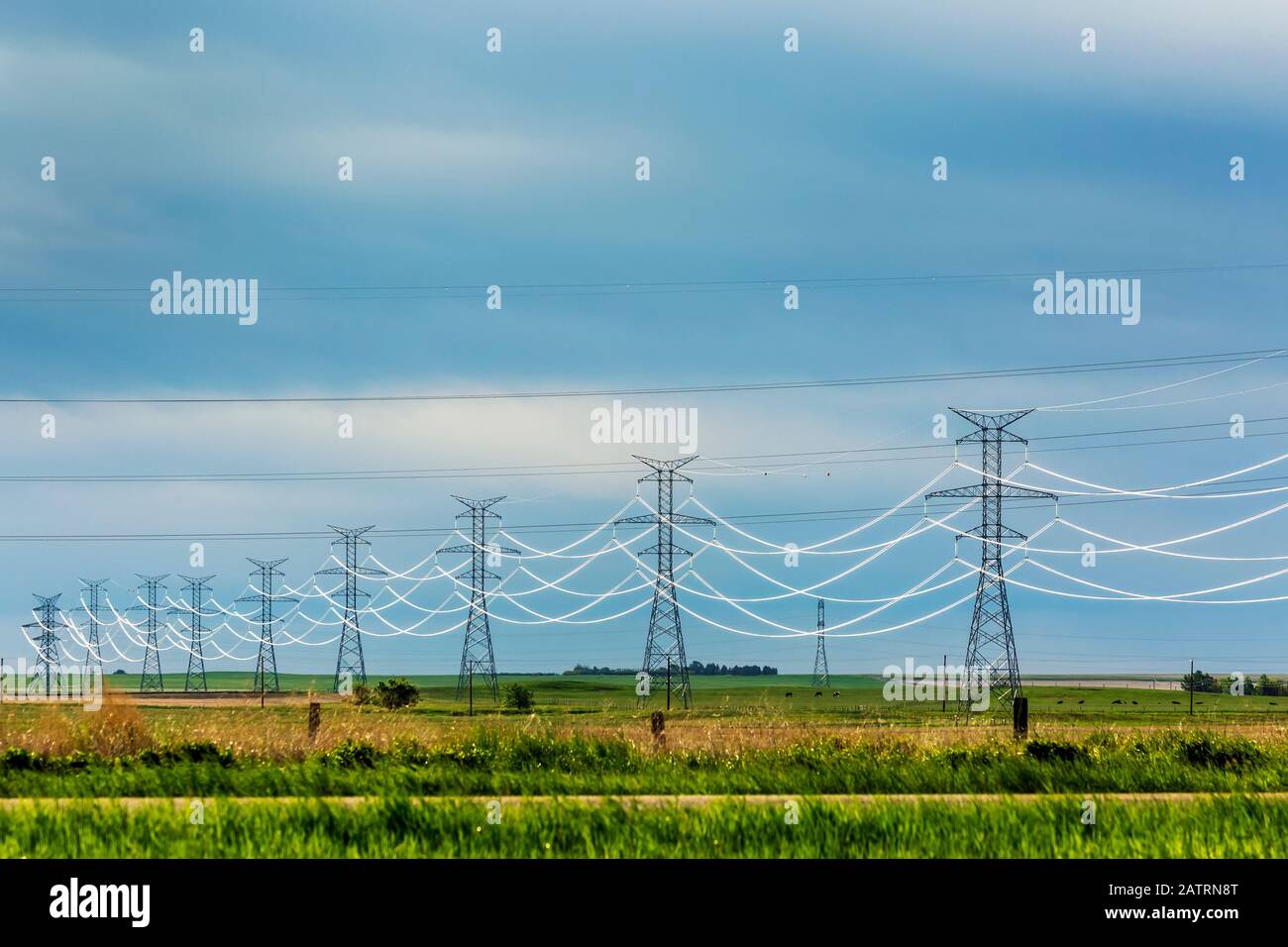 Highlighted power wires along large metal power towers with dark sky in ...