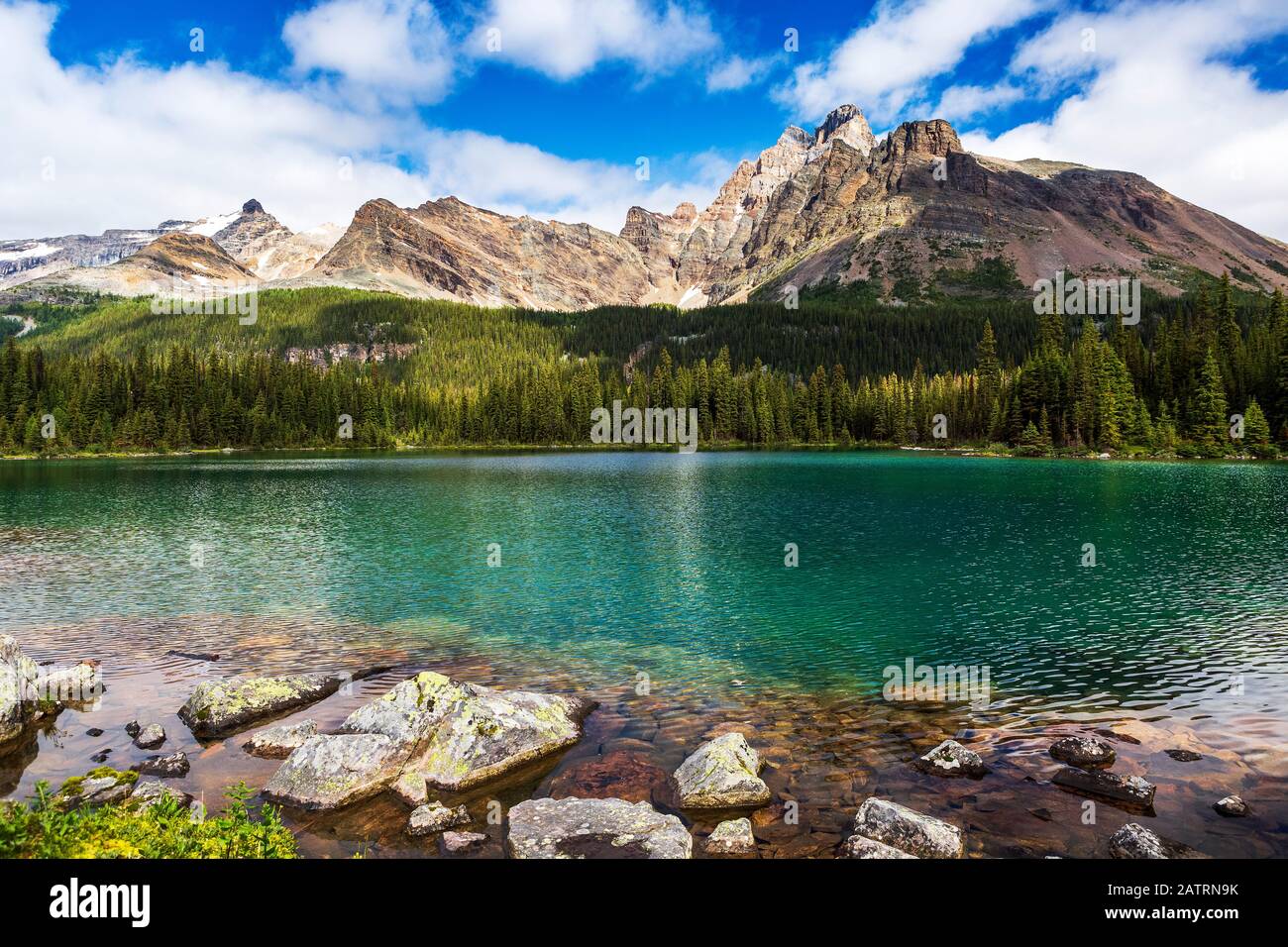 Alpine lake with rocky shoreline and mountain range in the distance ...