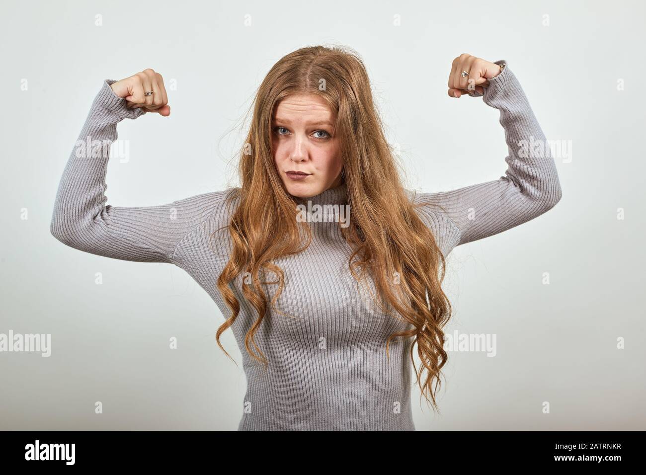 woman in gray shows her muscles on arms demonstrating strength ...