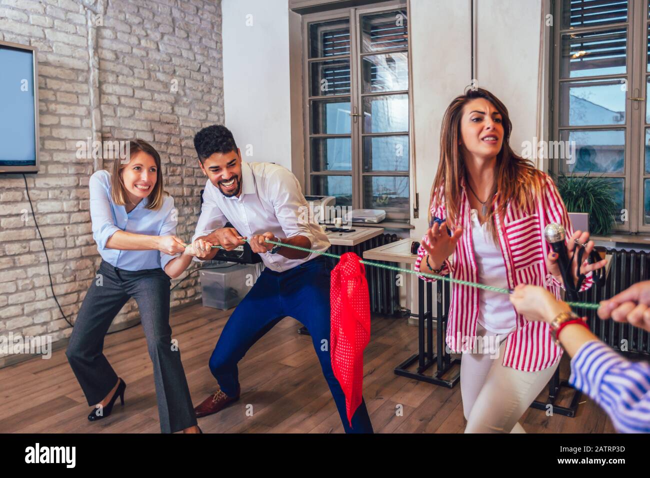 Business people pulling rope in office, funny teambuilding activity ...