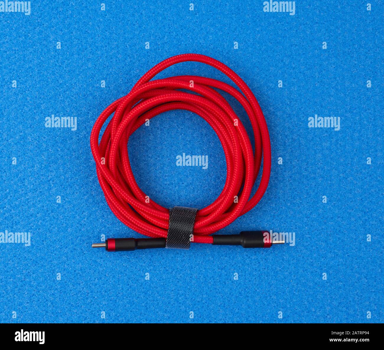twisted cable for charging mobile devices in a red textile wrapper on a ...