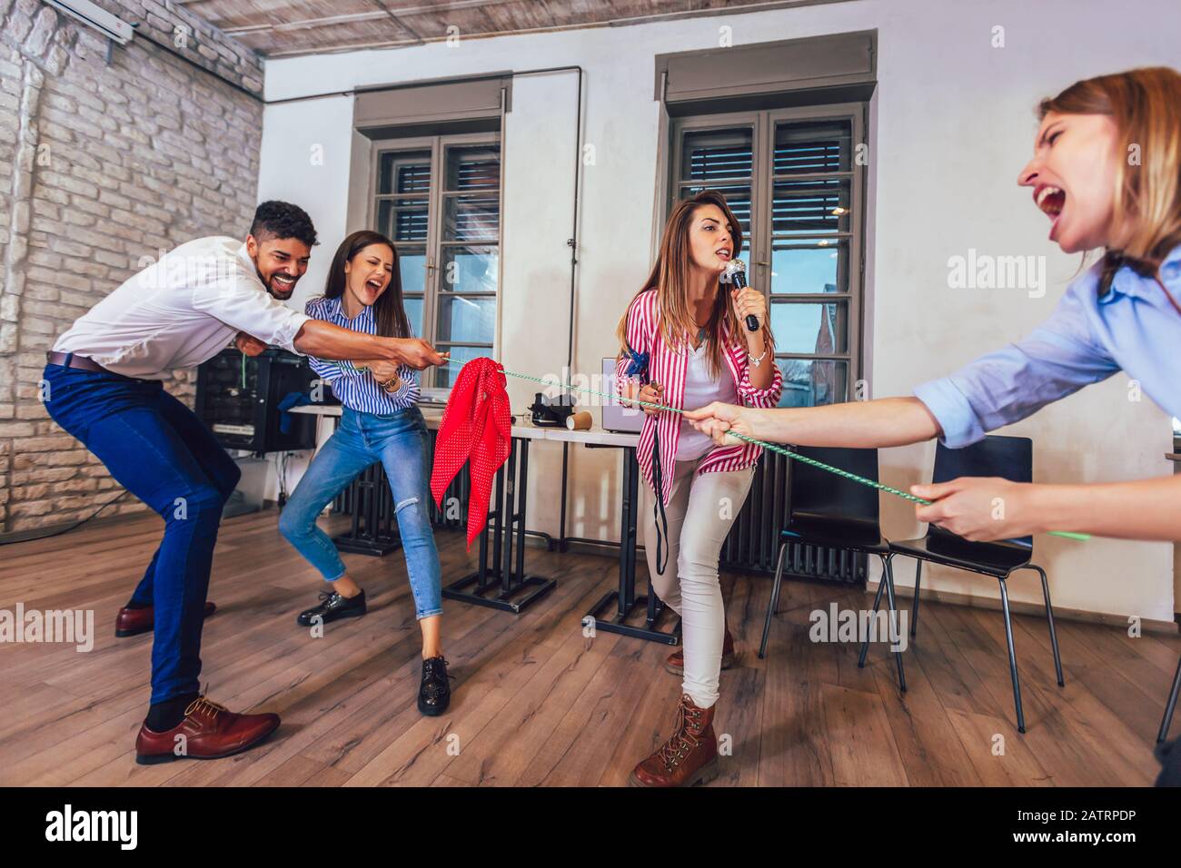 Business people pulling rope in office, funny teambuilding activity ...