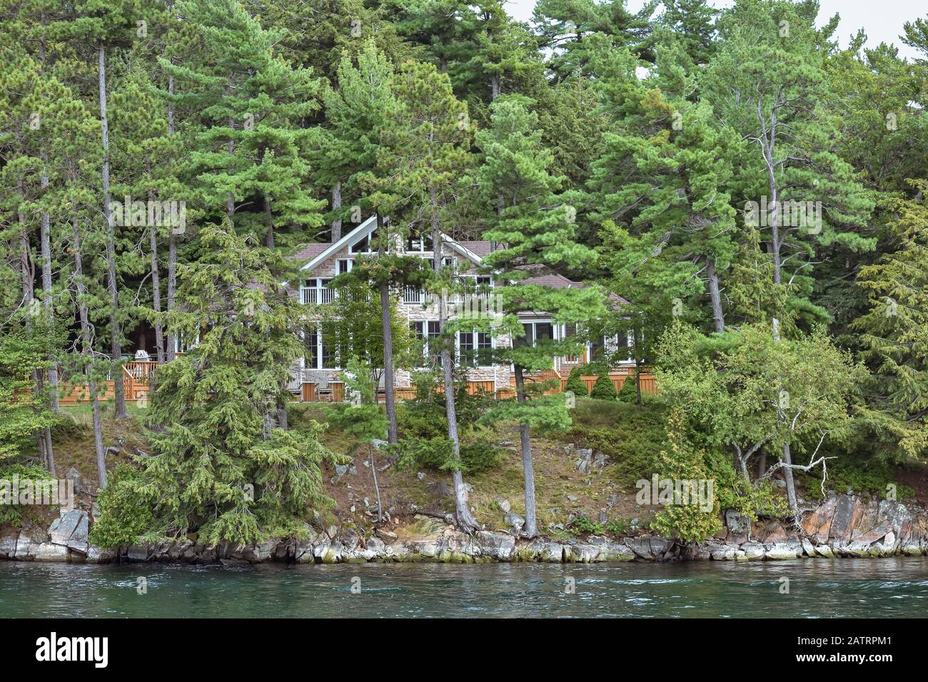 Isolated cottage in a rocky area on the coast of a lake during daytime ...