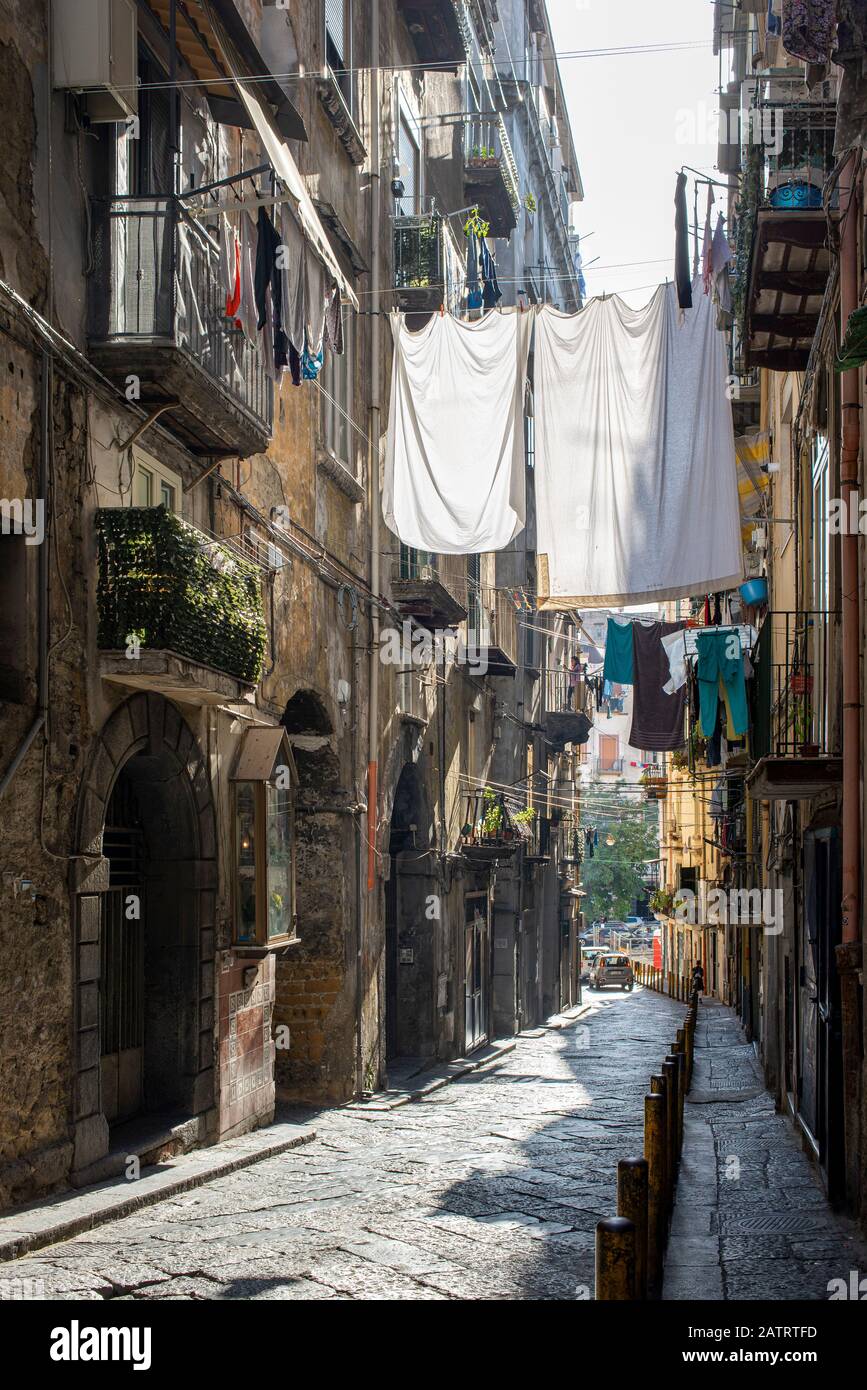 Bed sheets hanging between balconies over a cobbled side street in ...