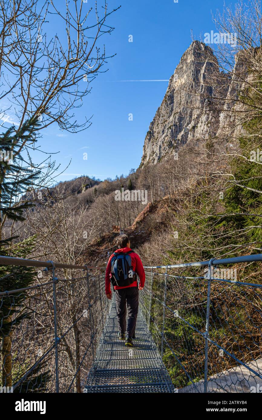 Hiker while crossing a Tibetan bridge located along a path on the ...