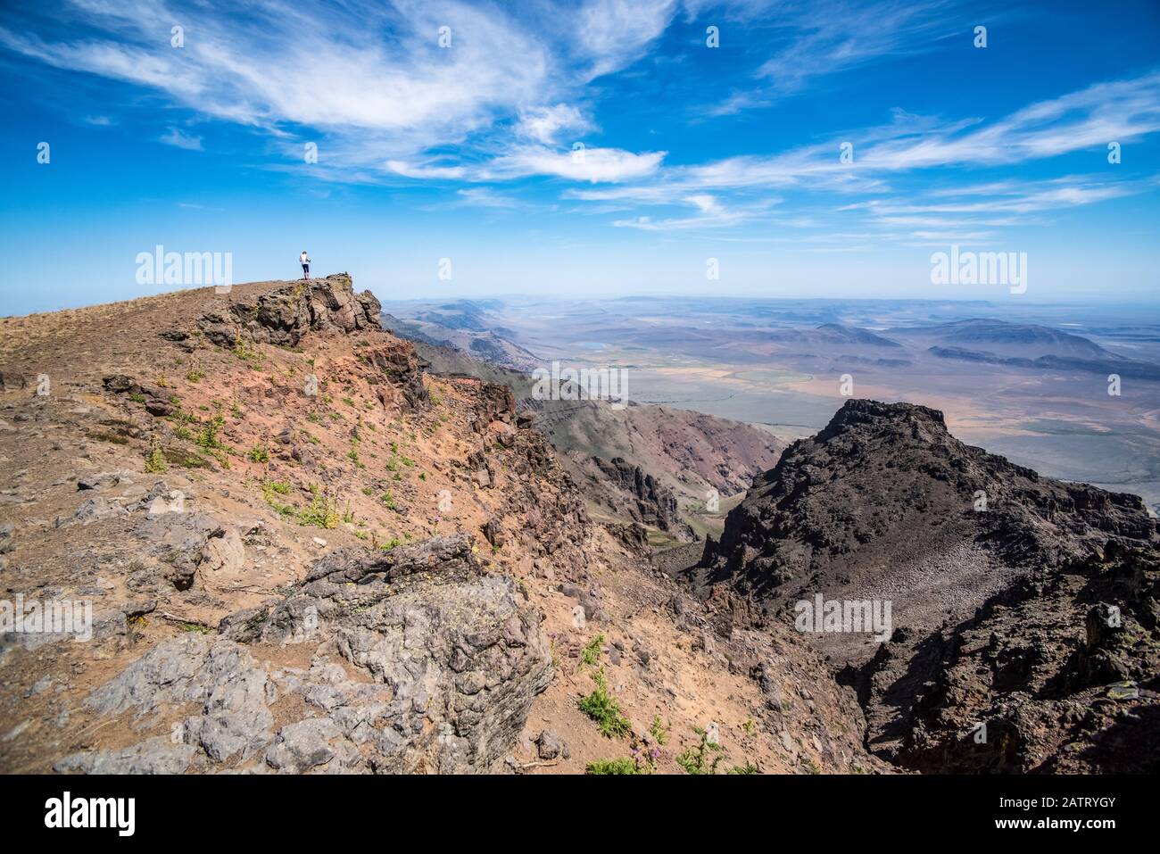 A woman looking out across the Alvord Desert from a cliffs edge on ...