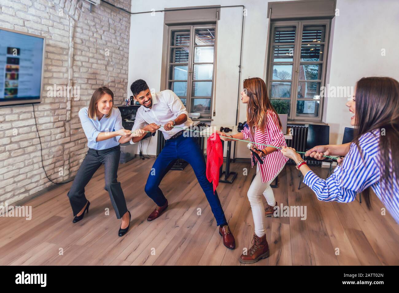 Business people pulling rope in office, funny teambuilding activity ...