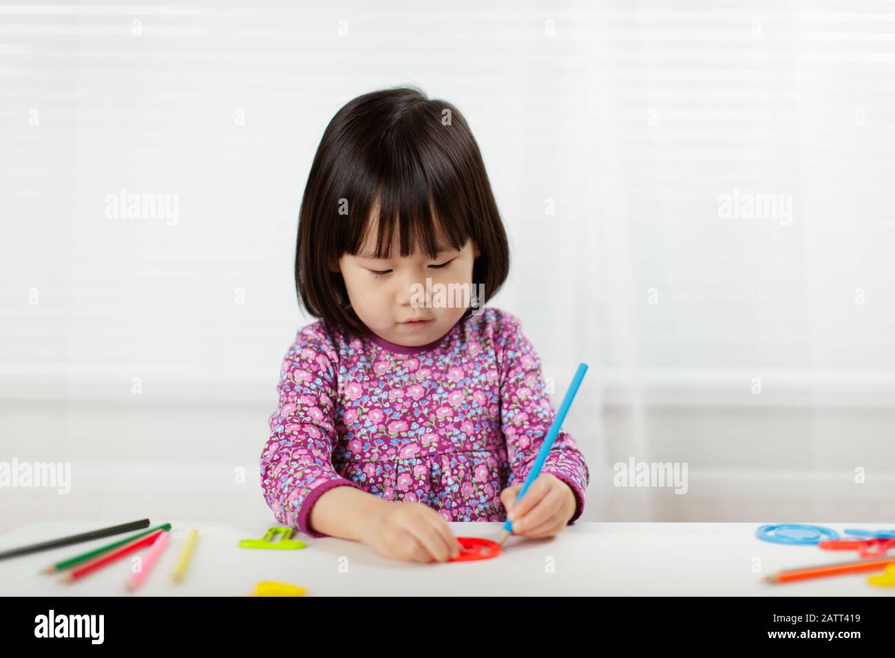 toddler girl practice writing letters on white paper against white ...