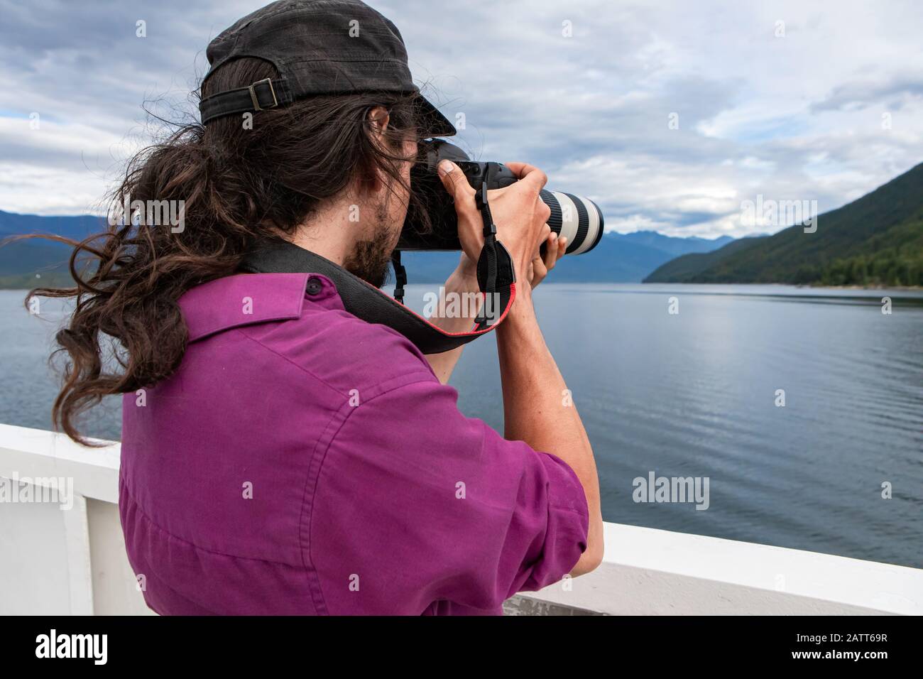 Young male photographer shot from behind, equipped with an expensive ...